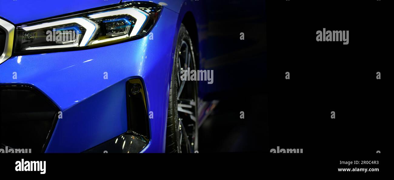 Front view of the LED headlights modern blue car on black background ...