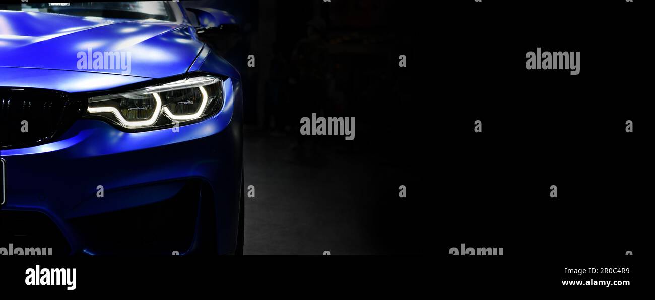 Front view of the LED headlights modern blue car on black background ...
