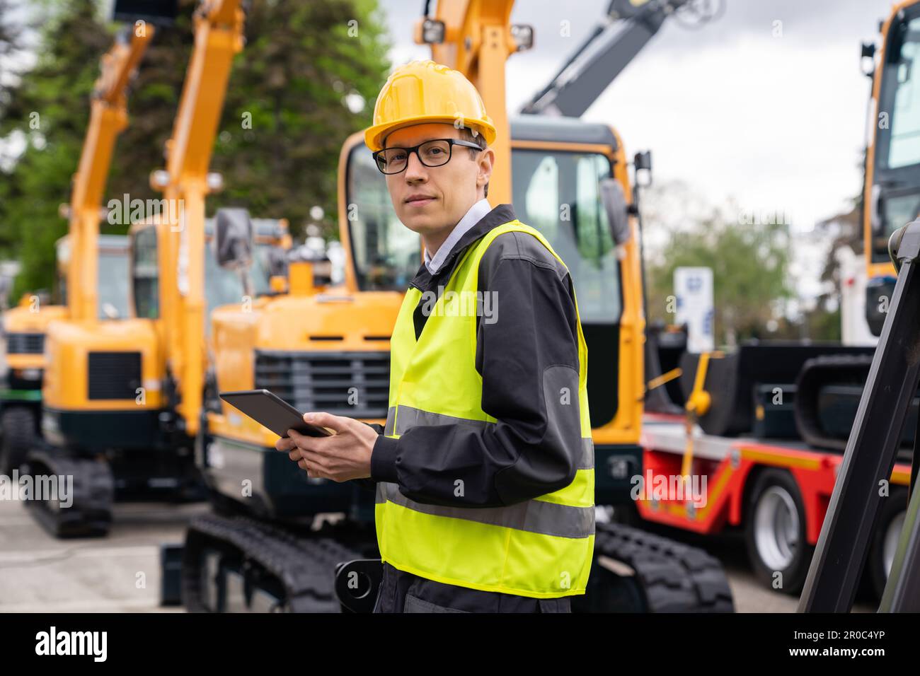 Engineer in a helmet with a digital tablet stands next to construction ...