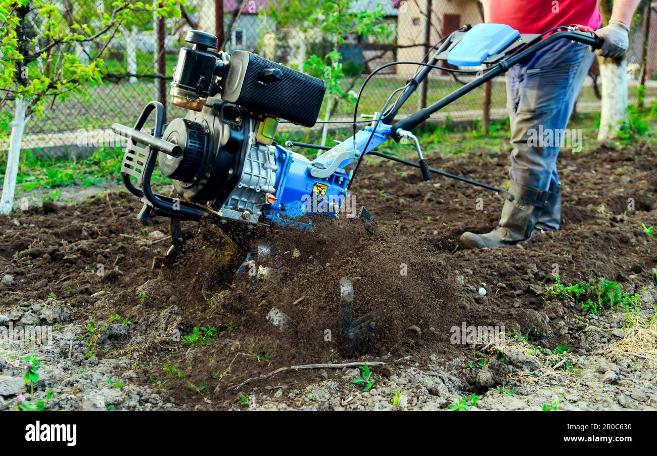 Farmer man works in the garden field with motor cultivator ...