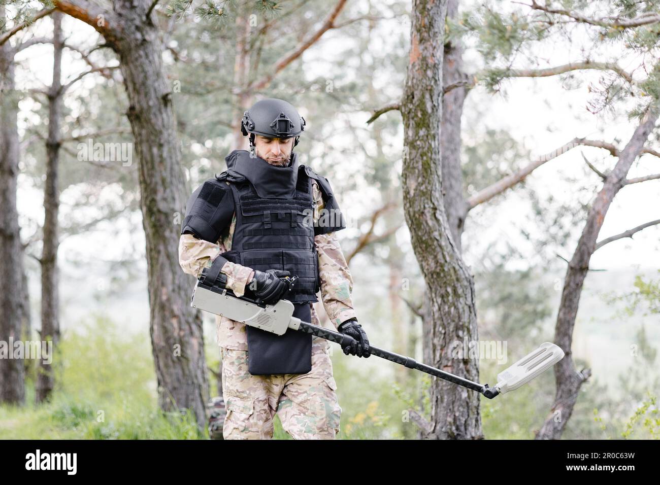A man in a military uniform and bulletproof vest works in the forest ...