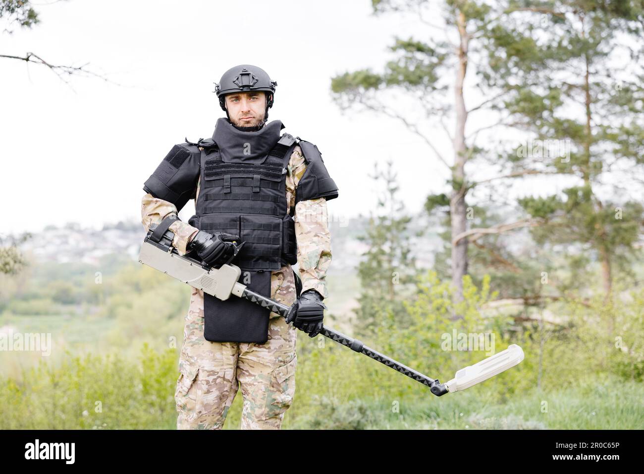 A man in a military uniform and bulletproof vest works in the forest ...