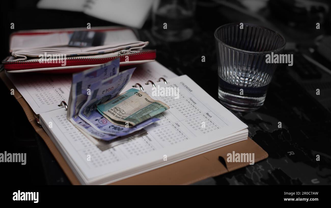 Indian rupee folded on a open monthly planer note book on a table with ...