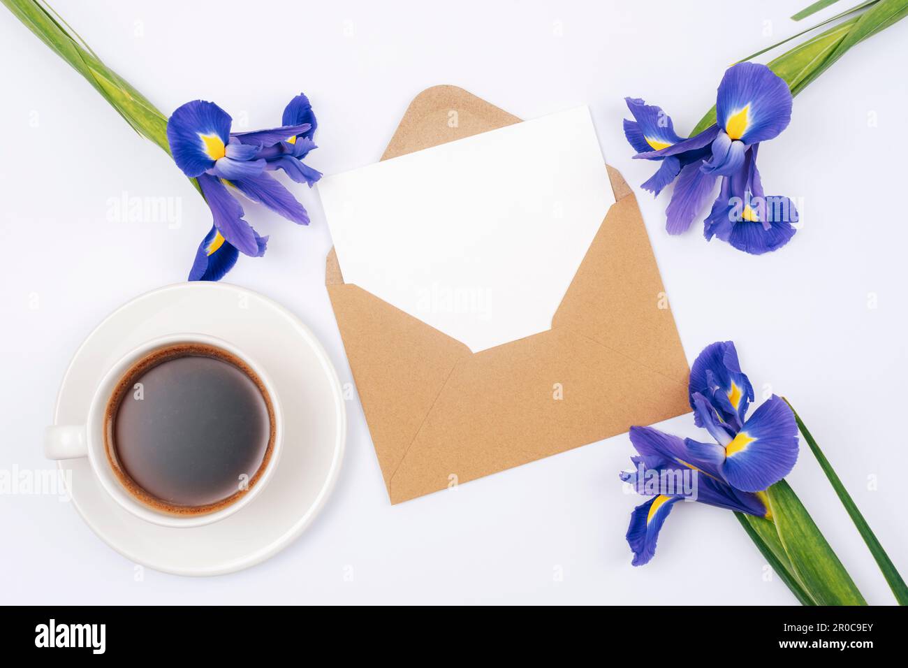 Coffee cup, envelope with blank paper and blue iris flowers on white ...