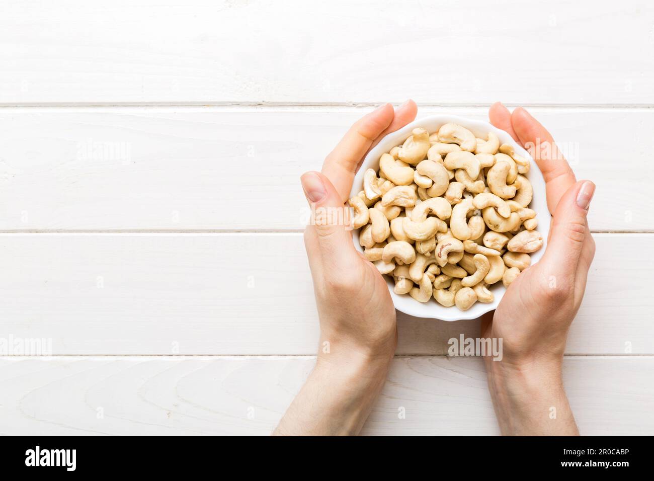 Woman hands holding a wooden bowl with cashew nuts. Healthy food and snack. Vegetarian snacks of ...