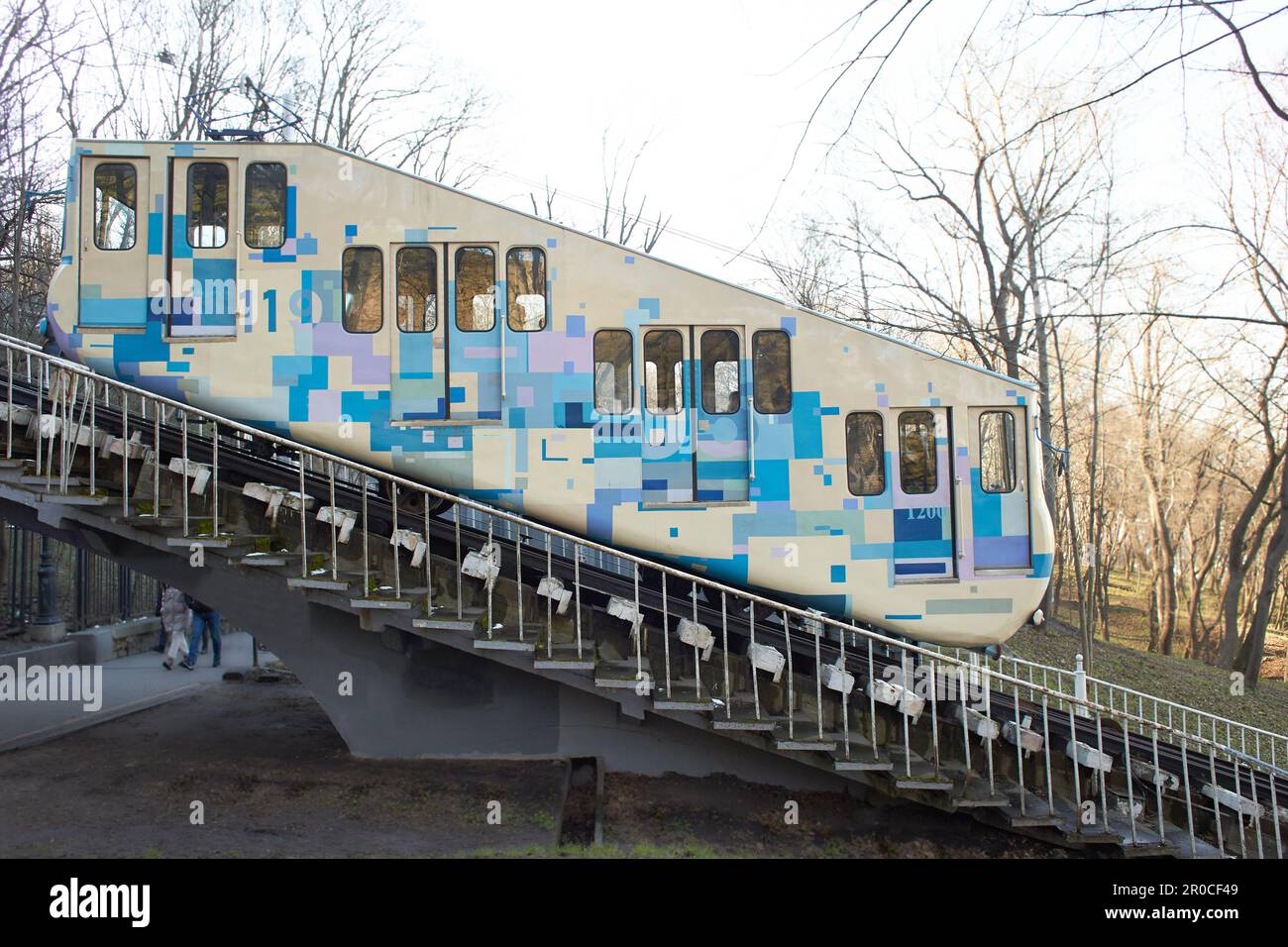 A blue and white cable funicular rises on rails along the slope ...