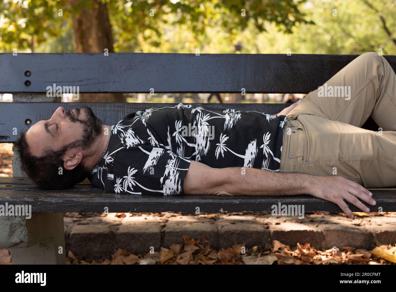 A man sleeping on a bench at the park Stock Photo - Alamy