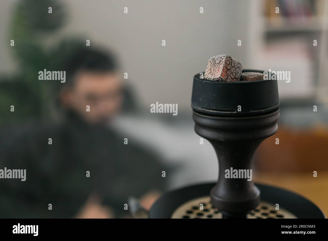 Bearded millennial or gen z man smoking hookah while relaxing on sofa ...