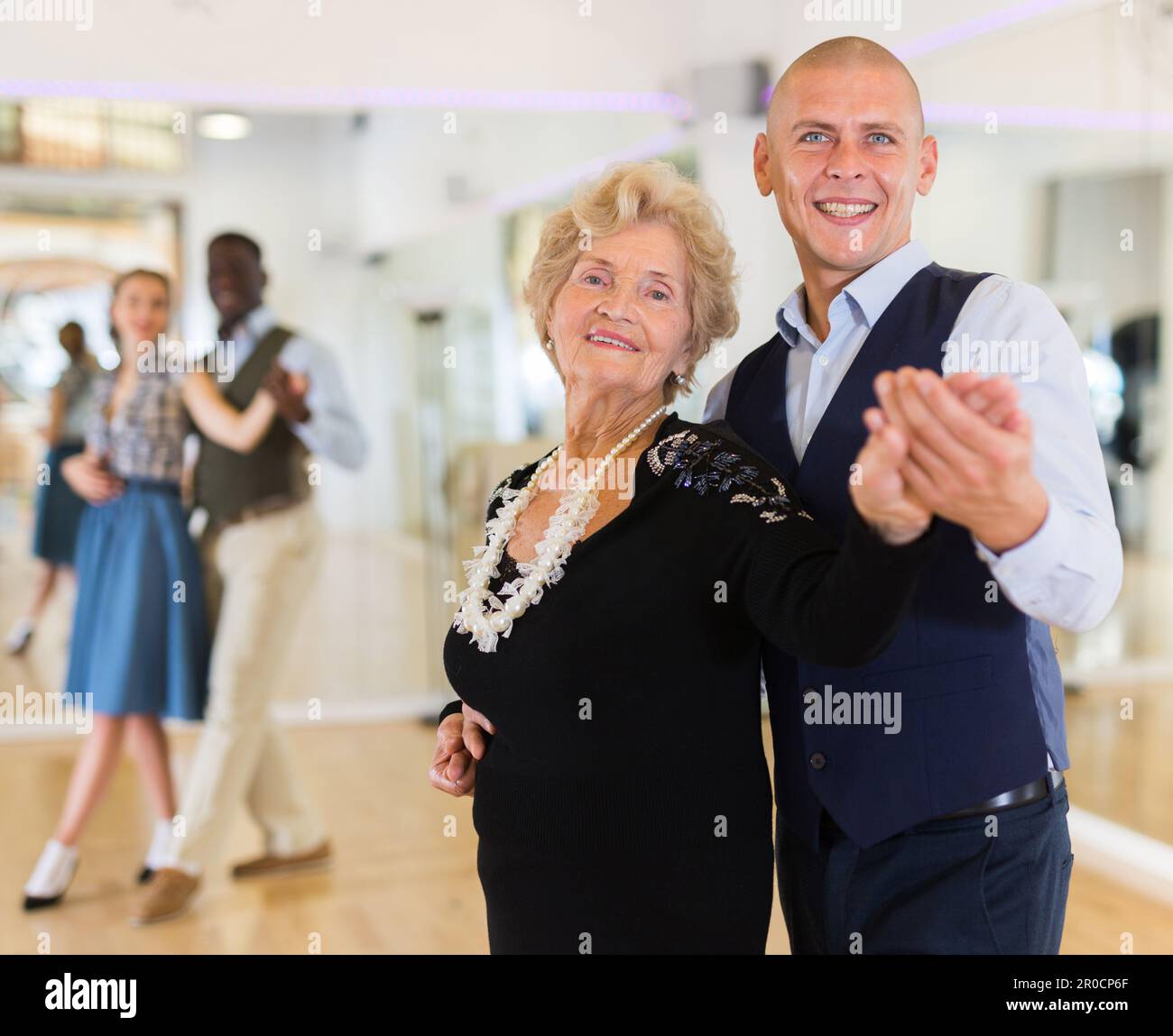 Man and elderly woman performing ballroom dance in dancing room Stock ...