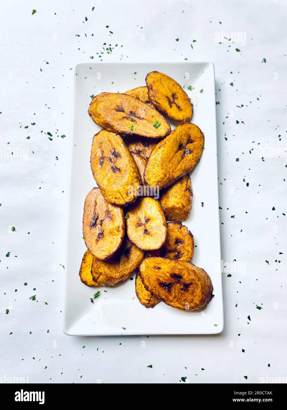 A plate of fried Jamaican plantains, with a side of tomatoes and ...