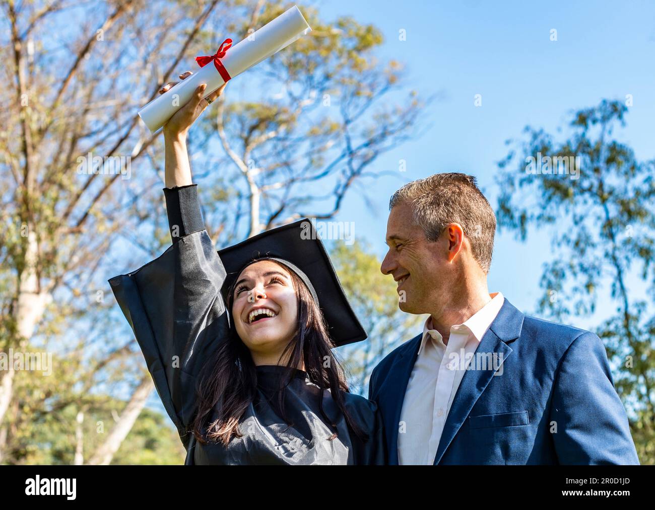 Happy graduated girl hugging her father while looking at her diploma on ...