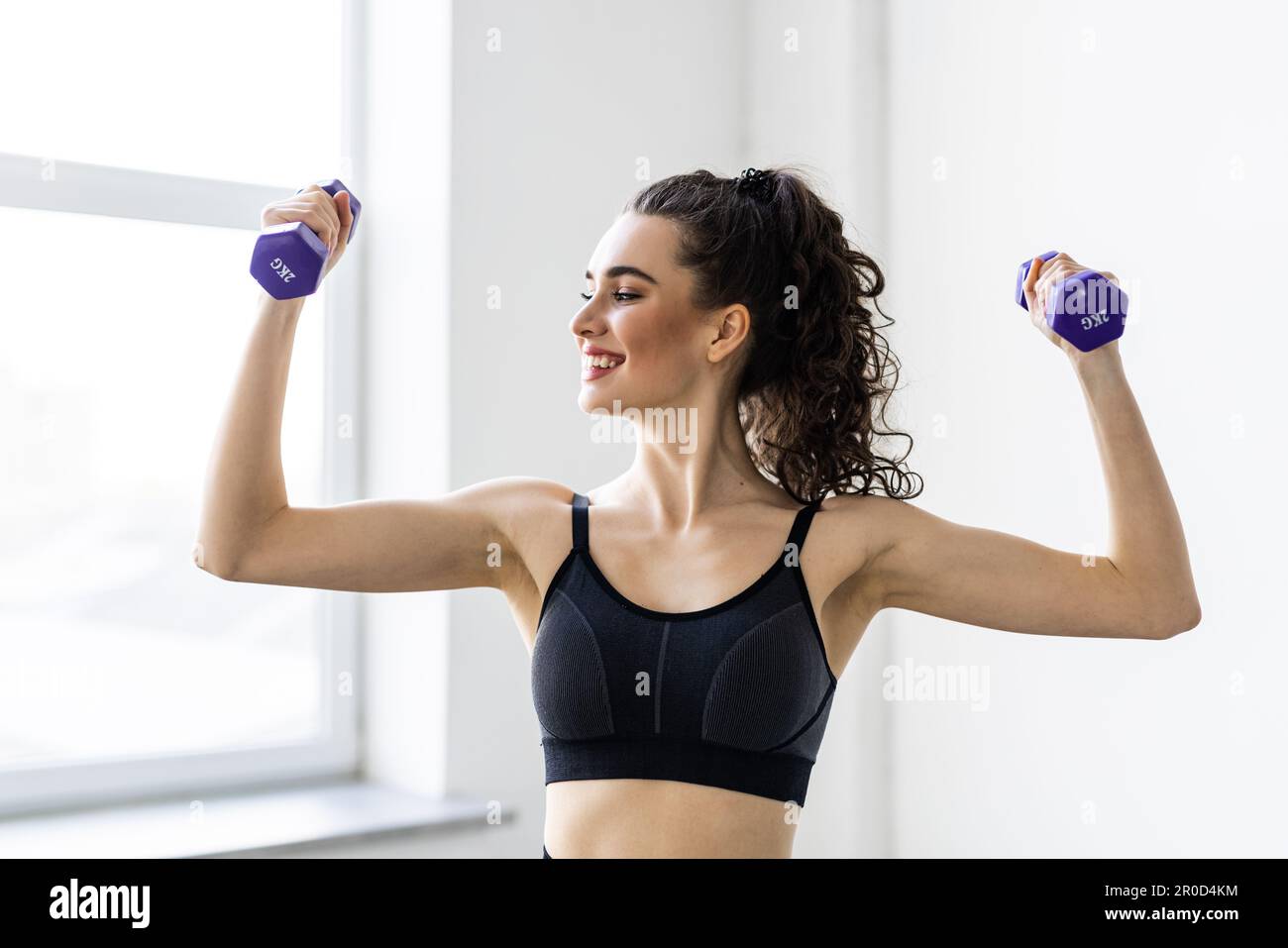 Photo of slim sporty woman doing exercises with small dumbbells at ...