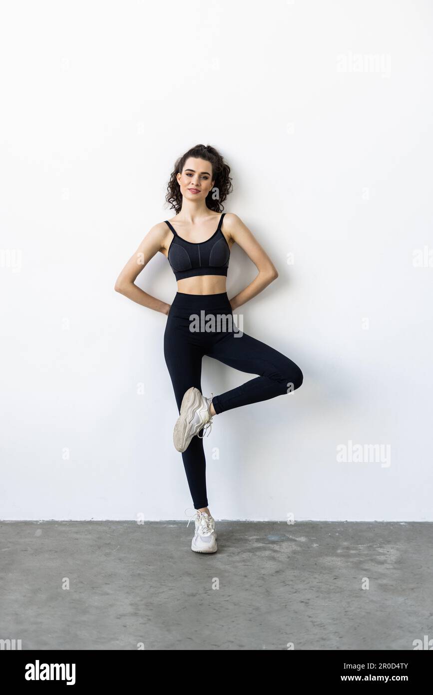 Confident sports woman in white sportsbra, holding hands on waist ...