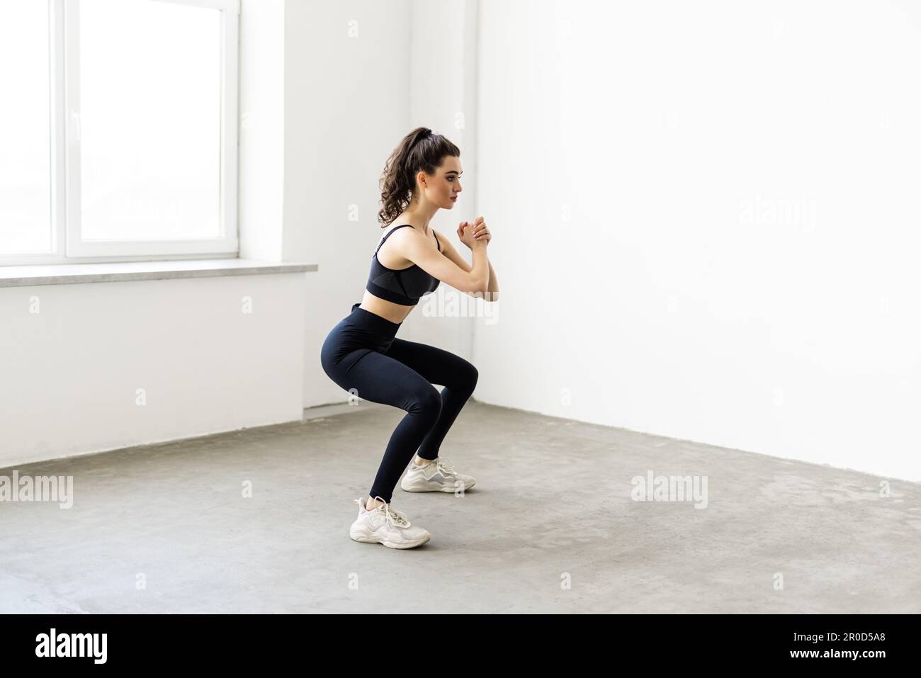 Young beautiful woman squats in studio Stock Photo - Alamy