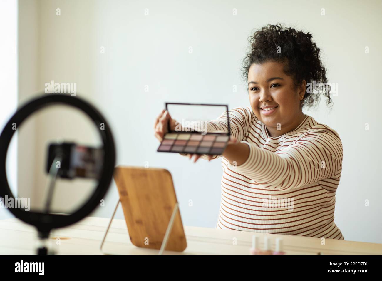 Cheerful young woman influencer recommending luxury eyeshadow palette ...