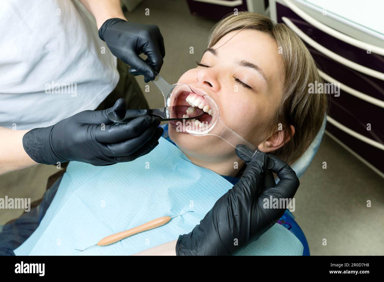 Doctor dentist with help of assistant examines oral cavity patient ...