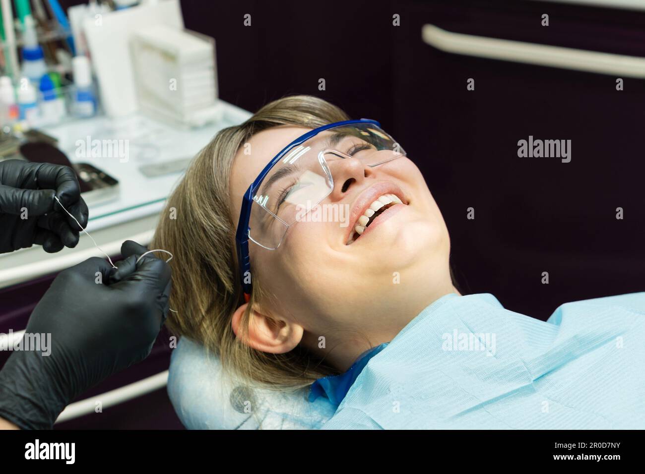 Satisfied and laughing female patient in dental chair. Dentist talks ...