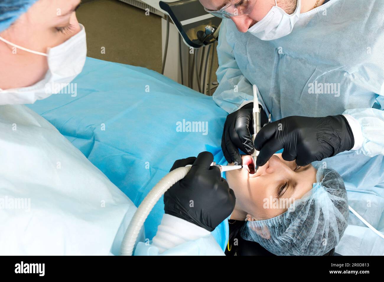 Surgeon and nurse during dental operation. Local anesthetized female patient in surgical room of ...