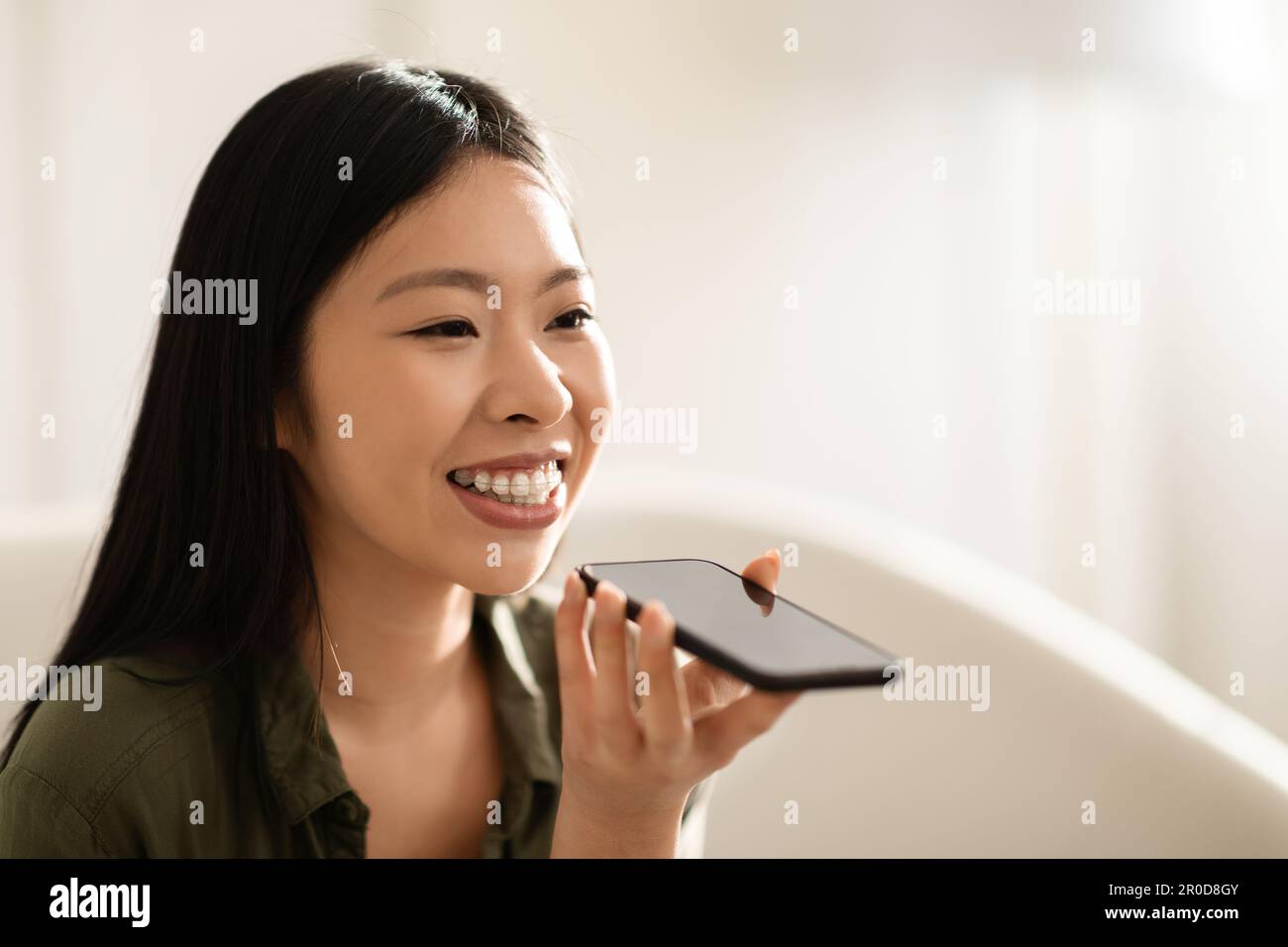 Cheerful young asian woman recording voice mail on phone Stock Photo ...