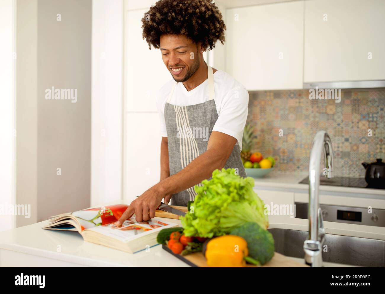 Happy Black Man Cooking Using Paper Recipe Book In Kitchen Stock Photo ...
