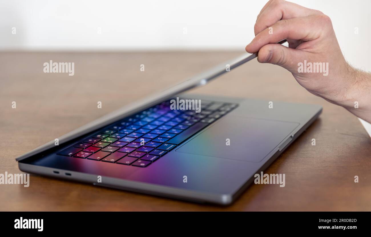 A man's hand opens a laptop with a multi-colored glowing screen Stock ...