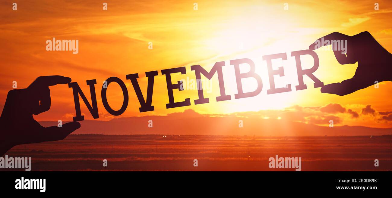 November - human hands holding black silhouette word Stock Photo - Alamy