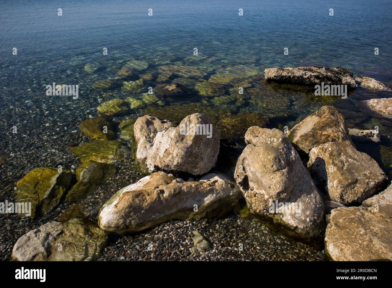A blue clean seaside with decorative large stones Stock Photo - Alamy