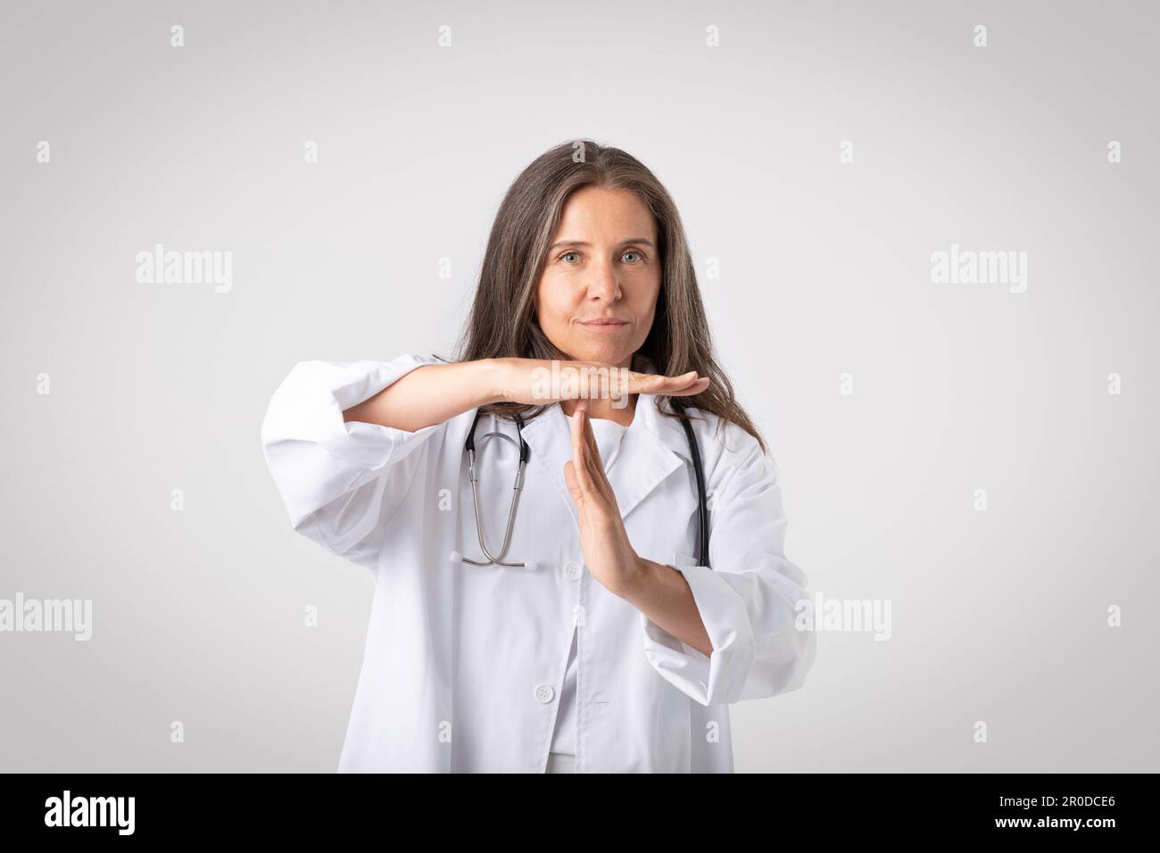 Senior doctor woman demonstrating time out gesture, highlighting the ...