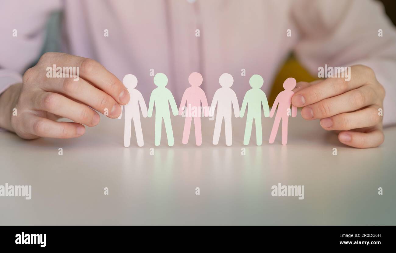 Holding paper human figures on light blue background, closeup with ... Holding paper human figures on light blue background, closeup with ...
