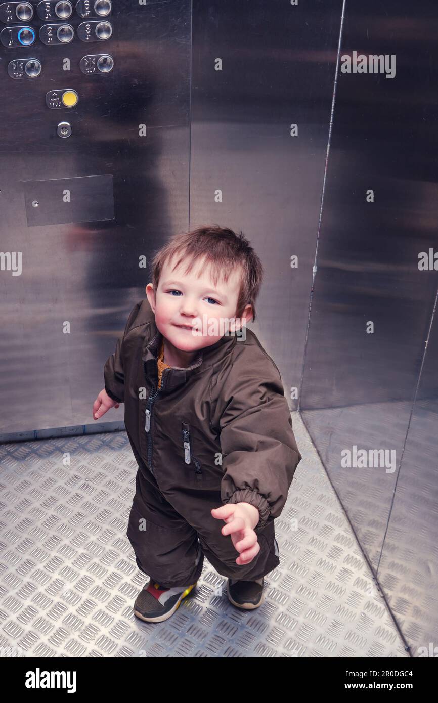 Happy small child rides in house elevator. Baby is standing in the ...