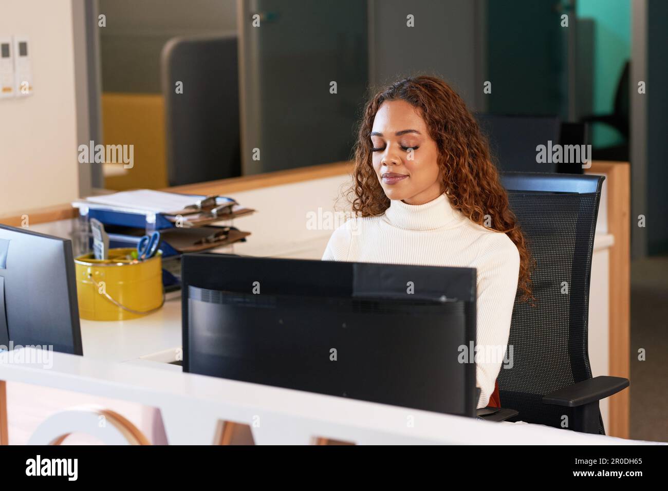 A busy young receptionist takes a moment to breathe and close her eyes ...