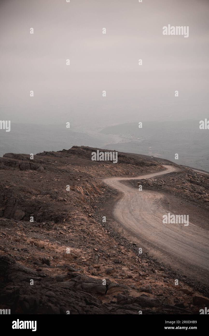 A winding dirt road leading up to a mountainous landscape of rolling ...