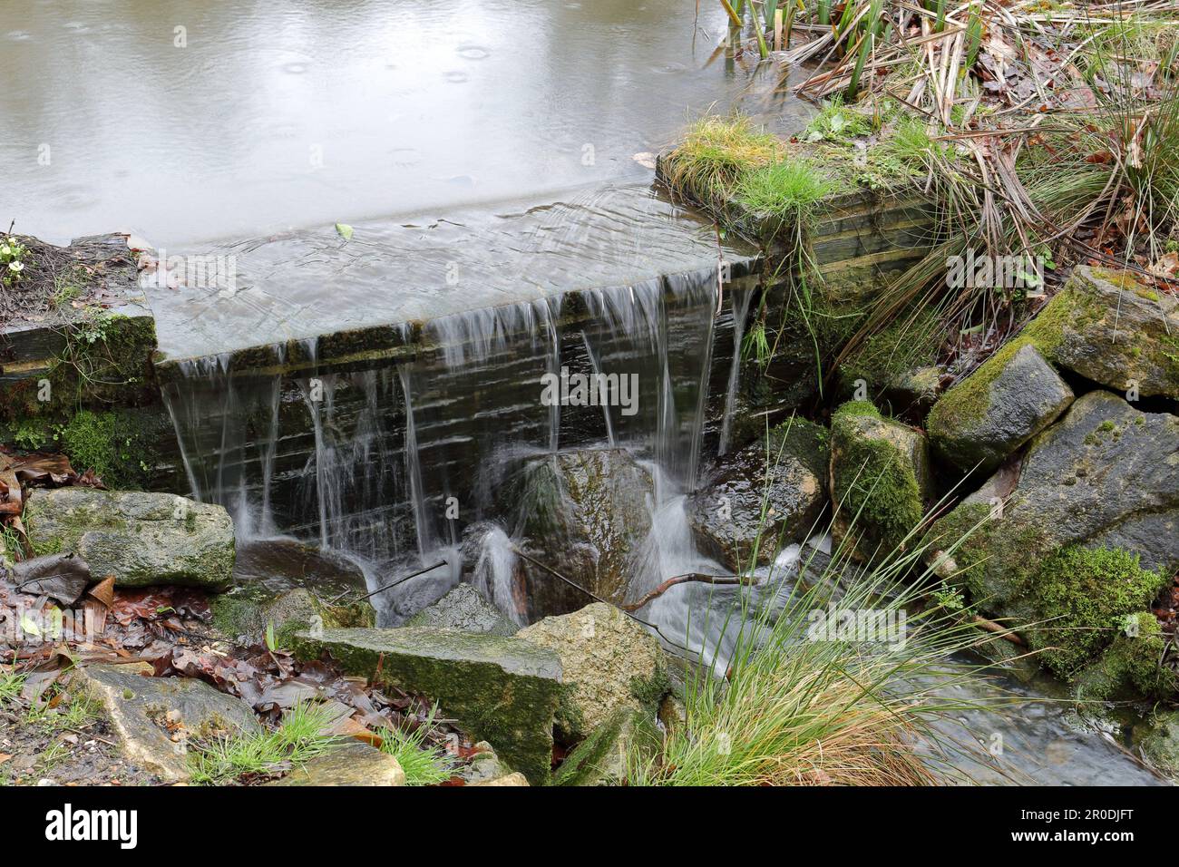 A small weir on a stream with rocks beneath Stock Photo - Alamy
