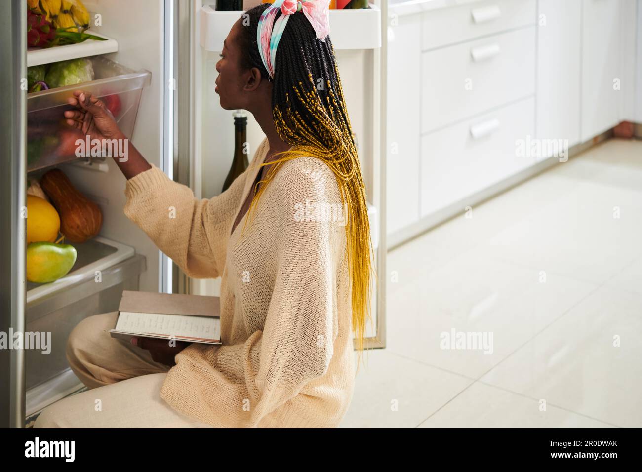 Woman taking ingredients for recipe from fridge Stock Photo - Alamy
