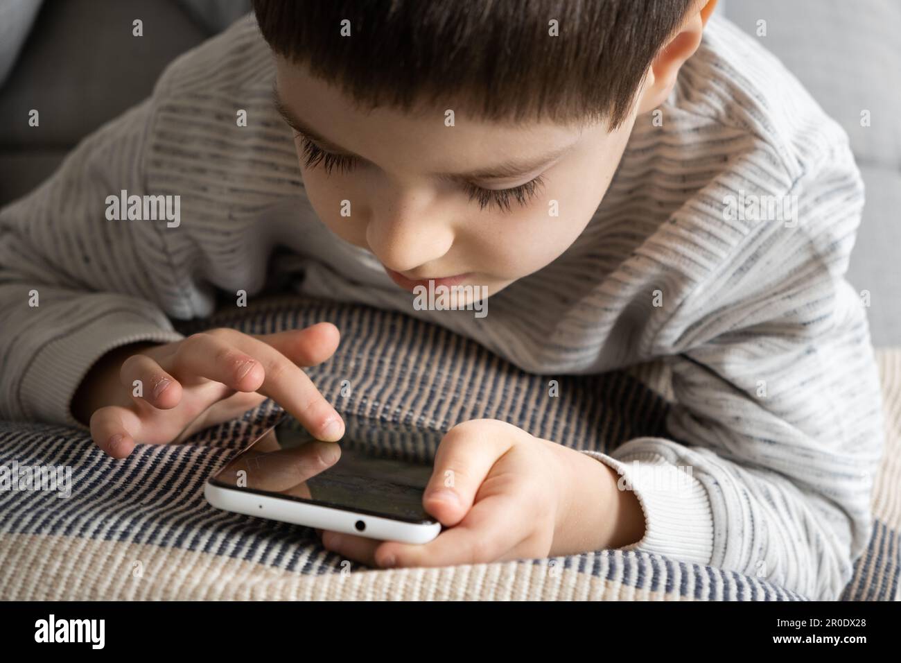 The child uses the phone, holds the smartphone in his hand and looks at ...