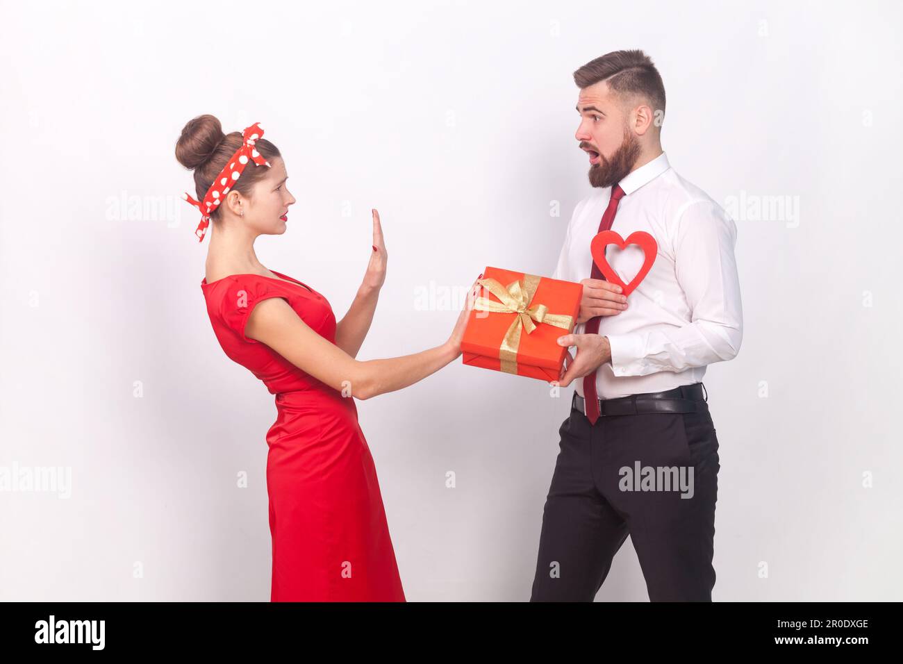 Portrait of shocked sad woman showing stop gesture to man with present ...