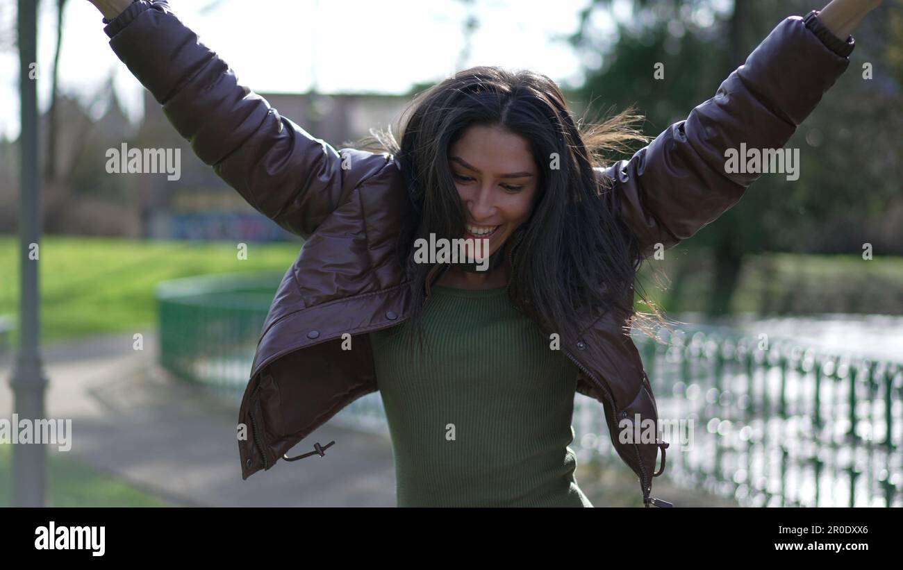 Happy young woman celebrates success with carefree dancing at the park ...