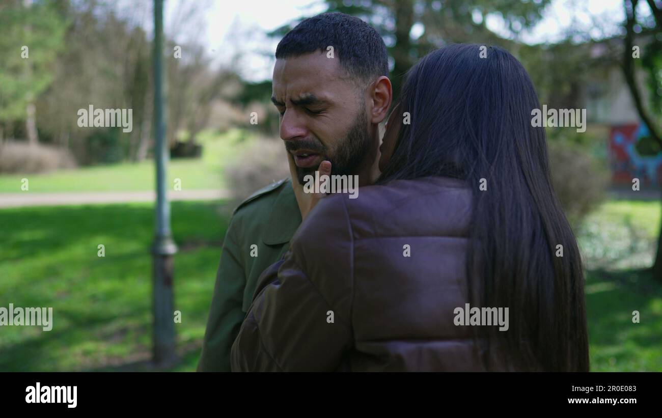 Depressed young man being consoled by woman embrace outside at park ...