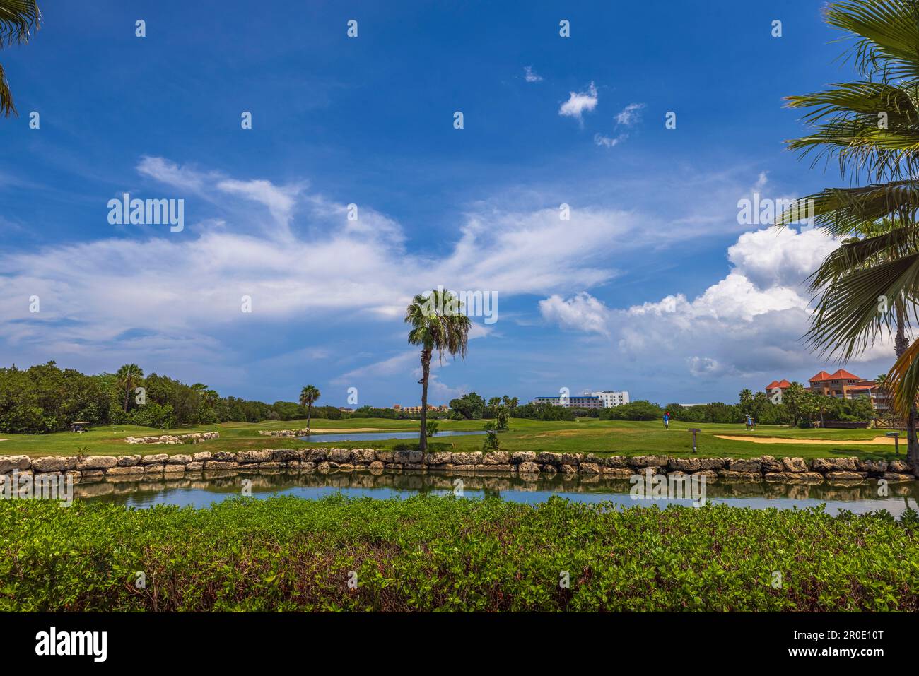 View of hotel building and blue water surface of pond and green grass ...