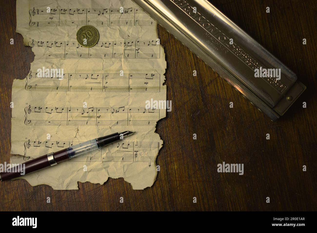 An antique ink pen lies atop a sheet of paper covered in musical notes ...