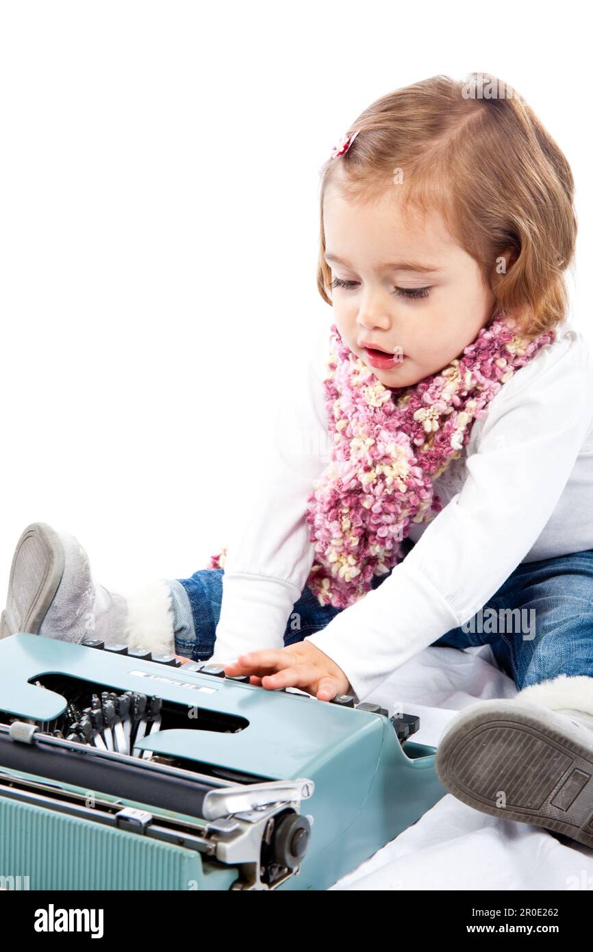 Beautiful little blonde girl playing with a typewriter Stock Photo - Alamy