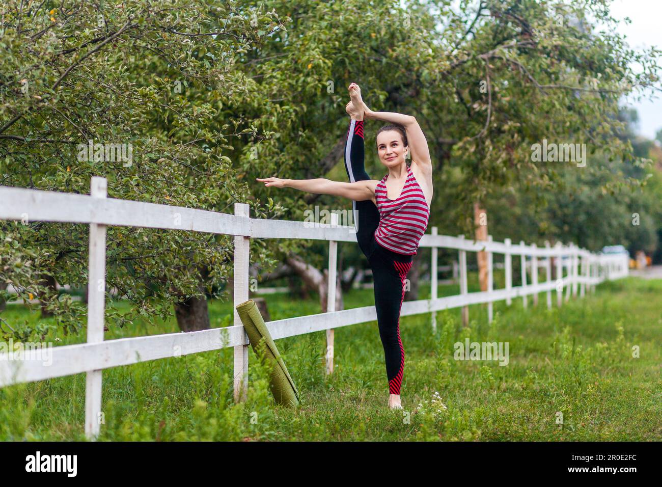 Full length portrait of flexible strong young girl stretching her leg ...