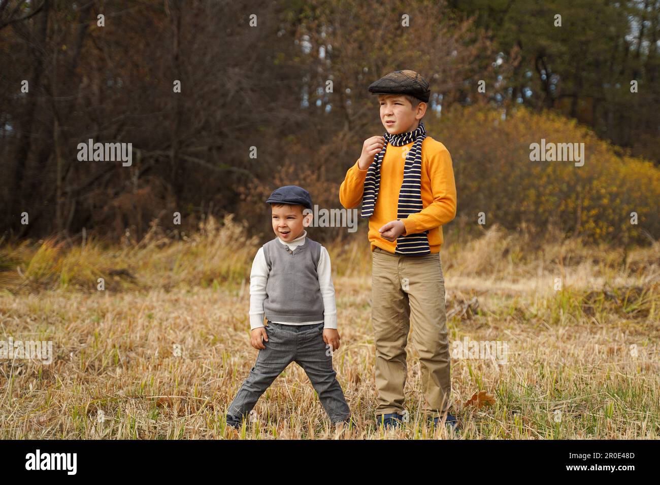 Two cute guys in retro clothes posing in a summer field and looking ...