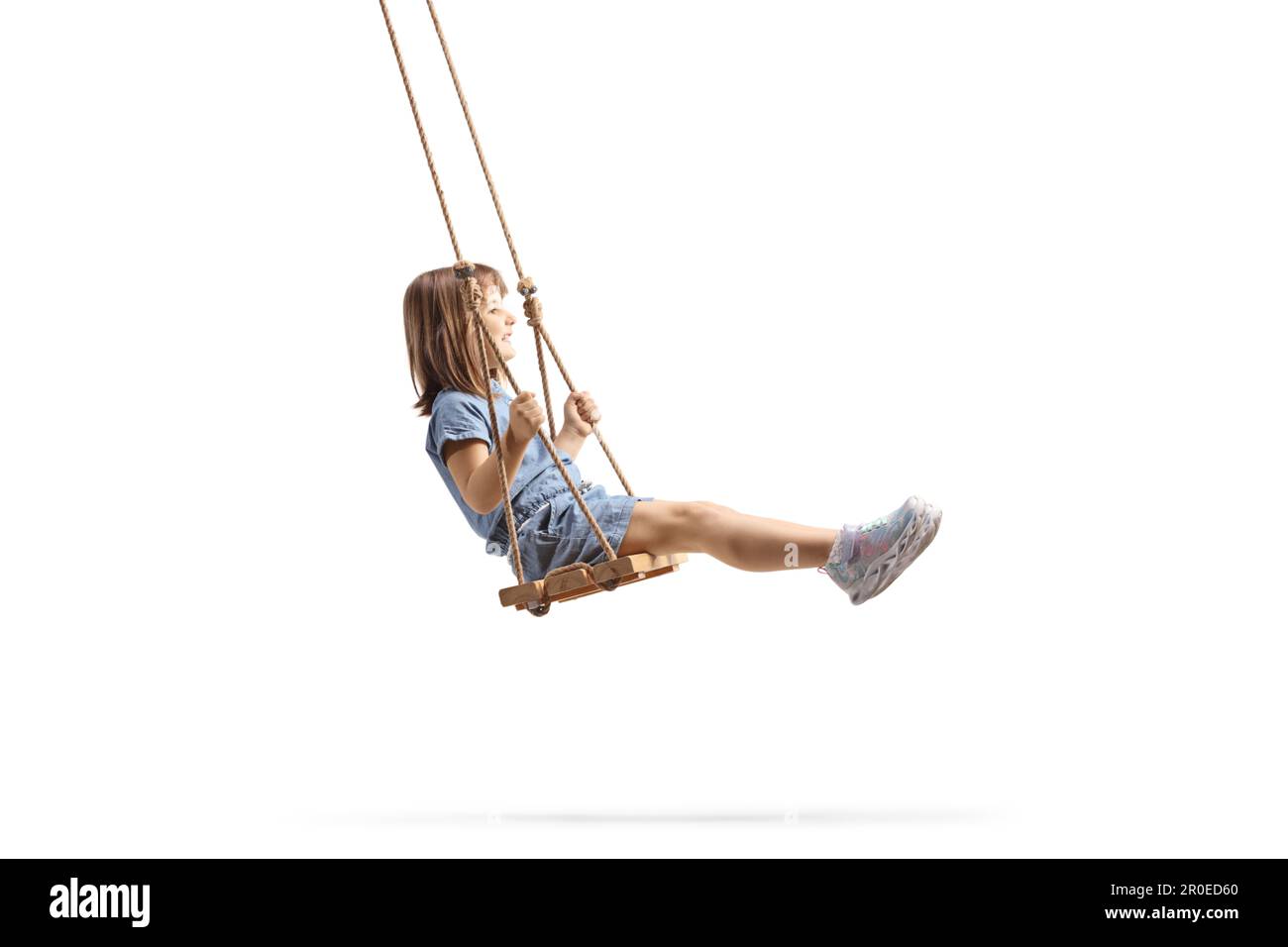 Full length profile shot of a happy little girl swinging on a wooden ...