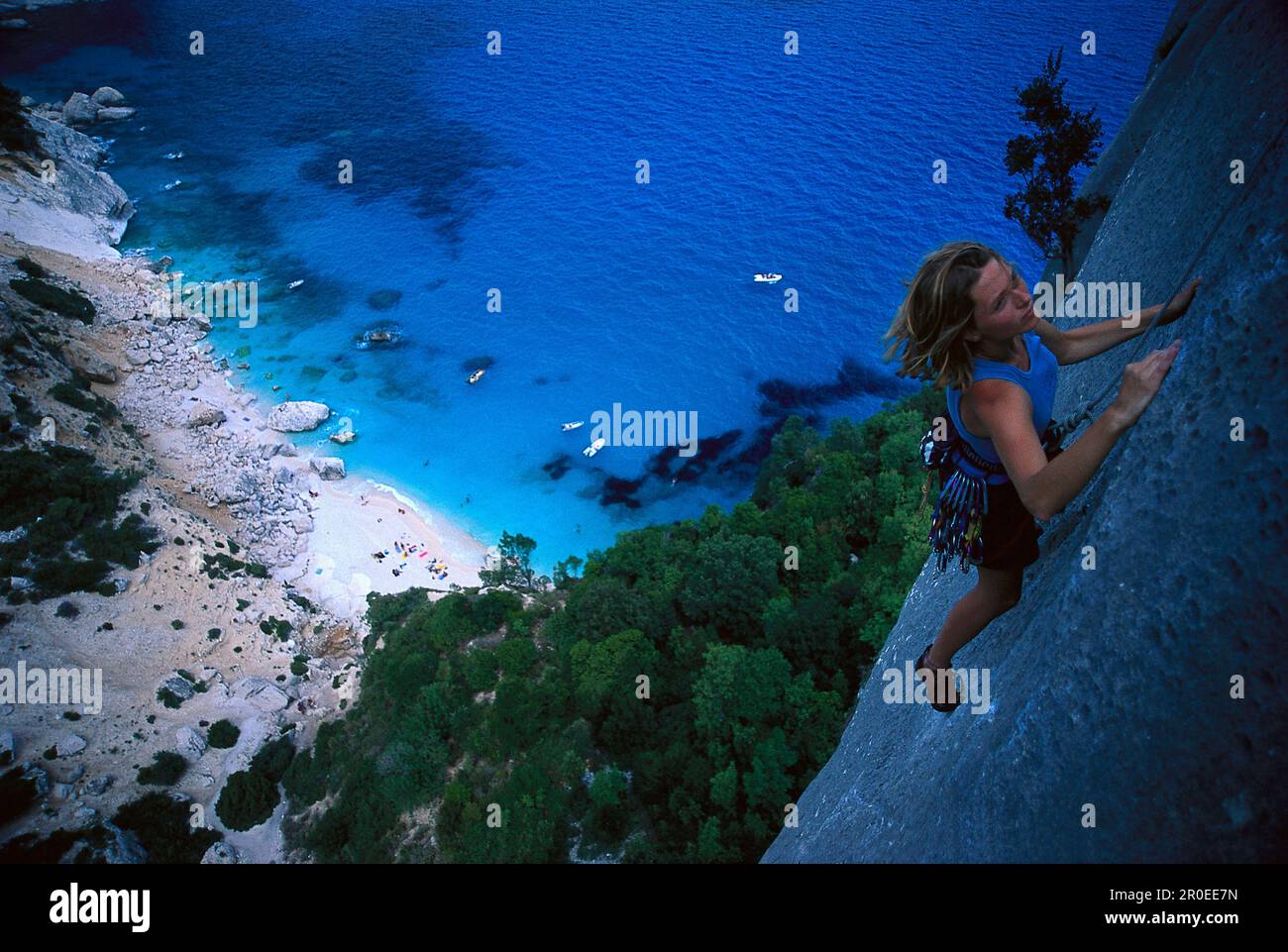 Female free climber scaling rock face, Cala Goloritze, Sardinia, Italy ...