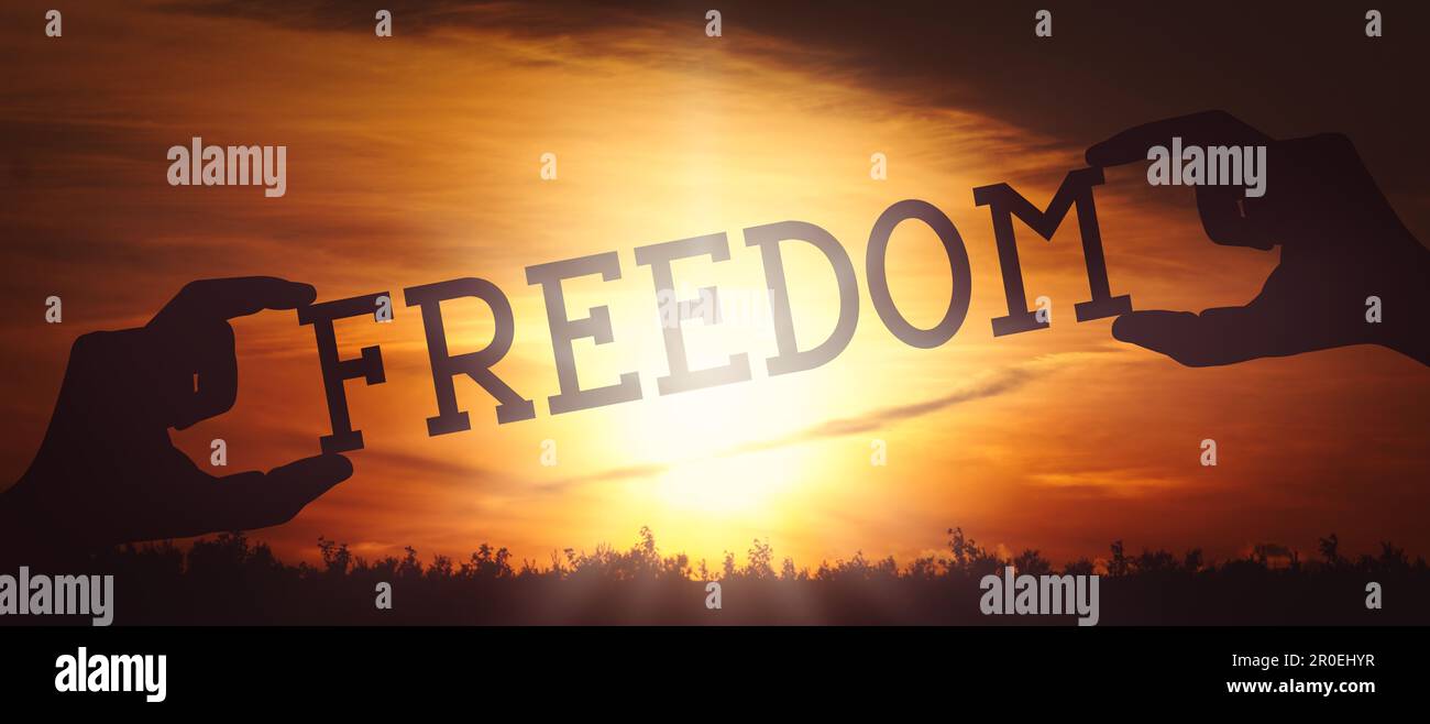 Freedom - human hands holding black silhouette word Stock Photo - Alamy
