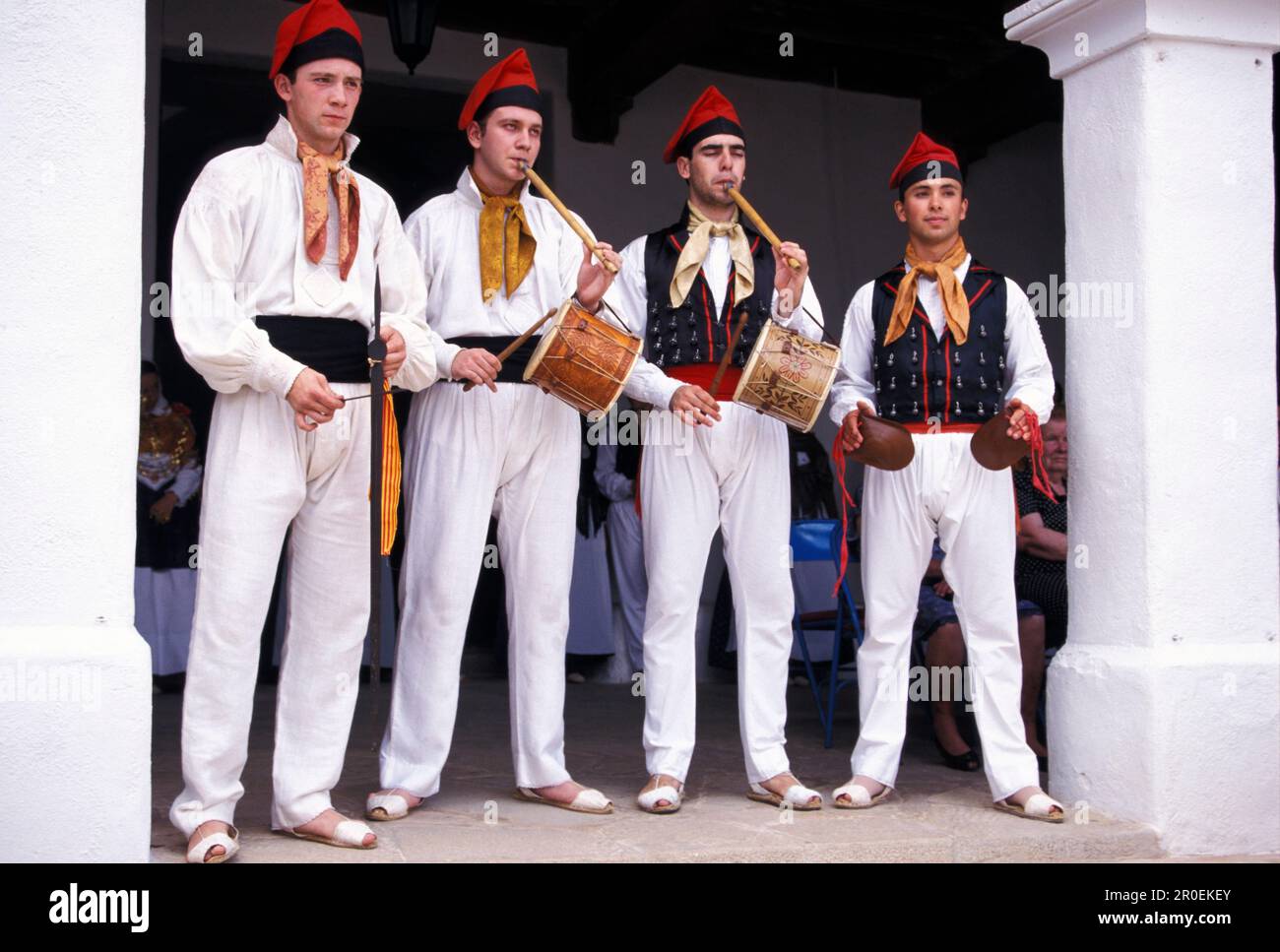 Four men wearing traditional clothes and playing tradional misic ...