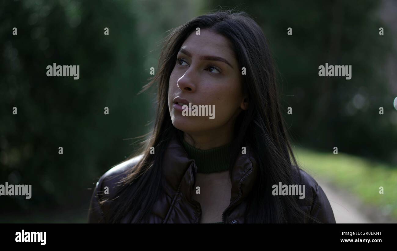 One contemplative young woman walking outside at park feeling ...