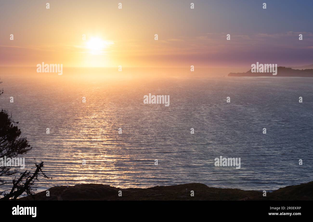 Sunset off the coast of California, the ocean is calm and light from ...