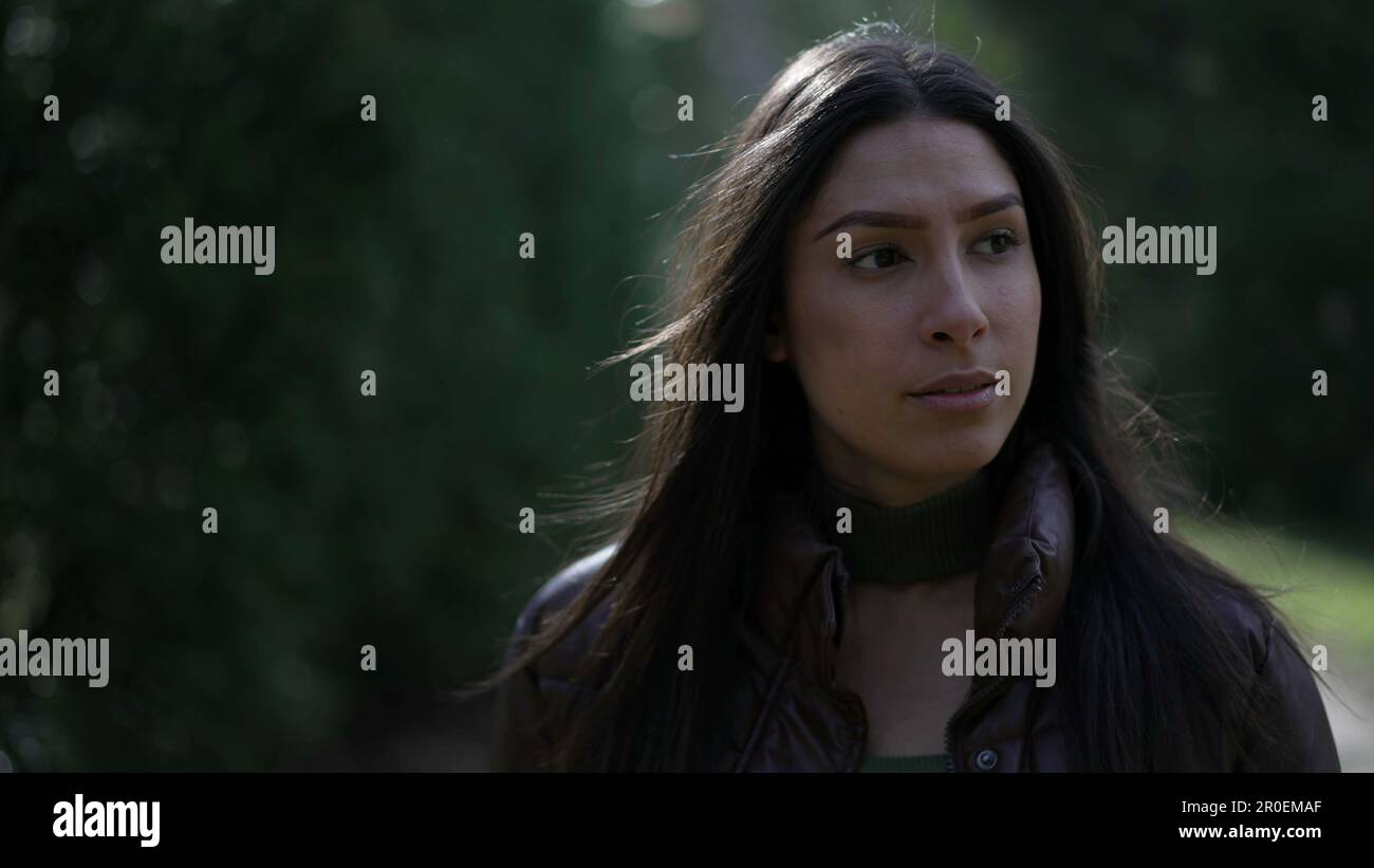 One contemplative young woman walking outside at park feeling ...